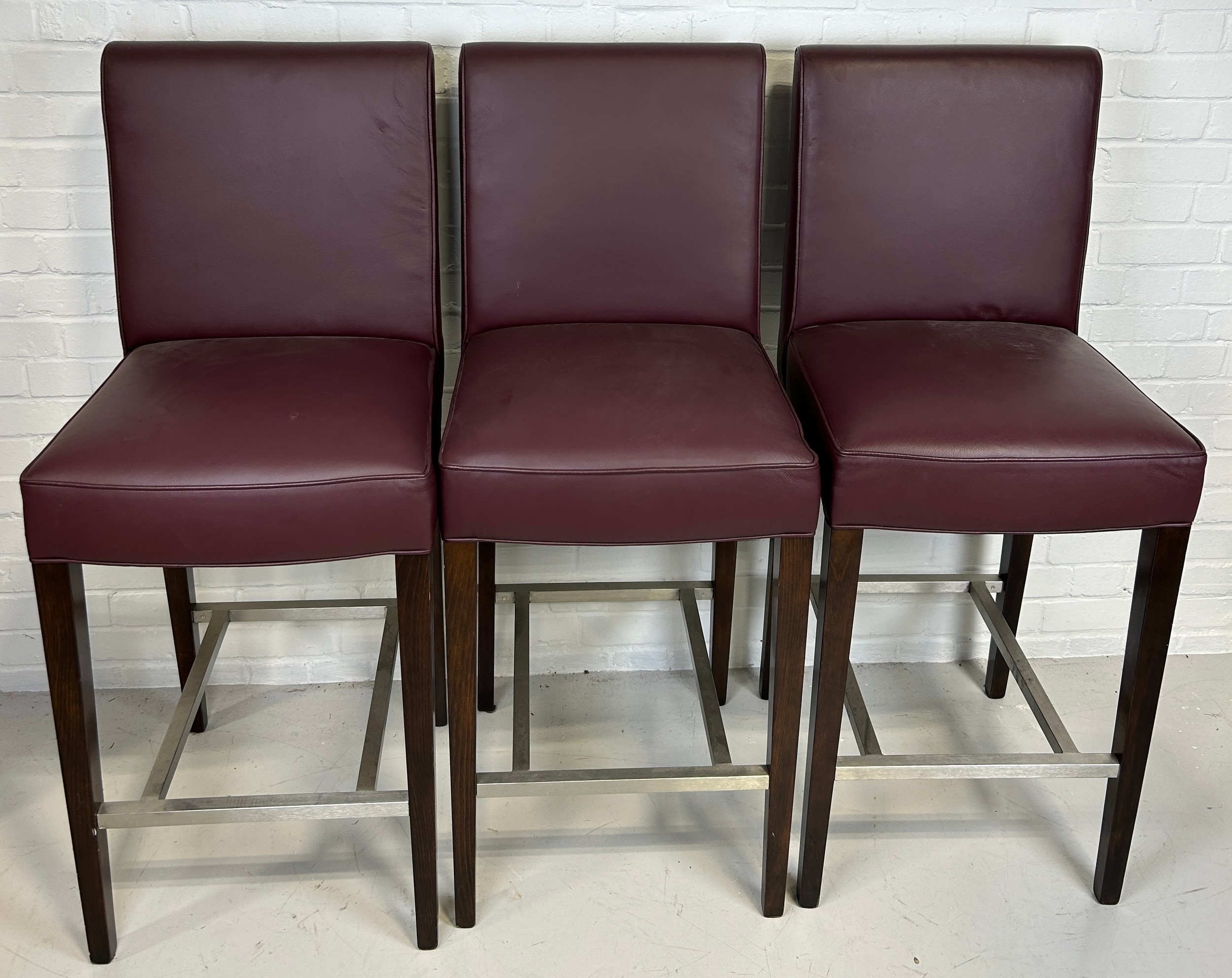 A SET OF THREE BAR STOOLS BY BEN WHISTLER UPHOLSTERED IN BURGUNDY ...