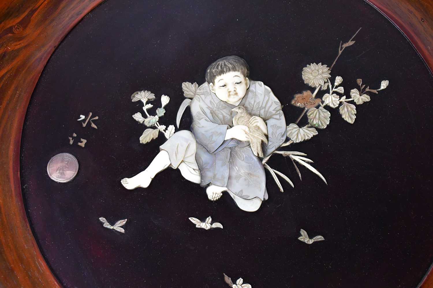 A Japanese Shibayama roundel depicting a boy holding a bird, amongst ...