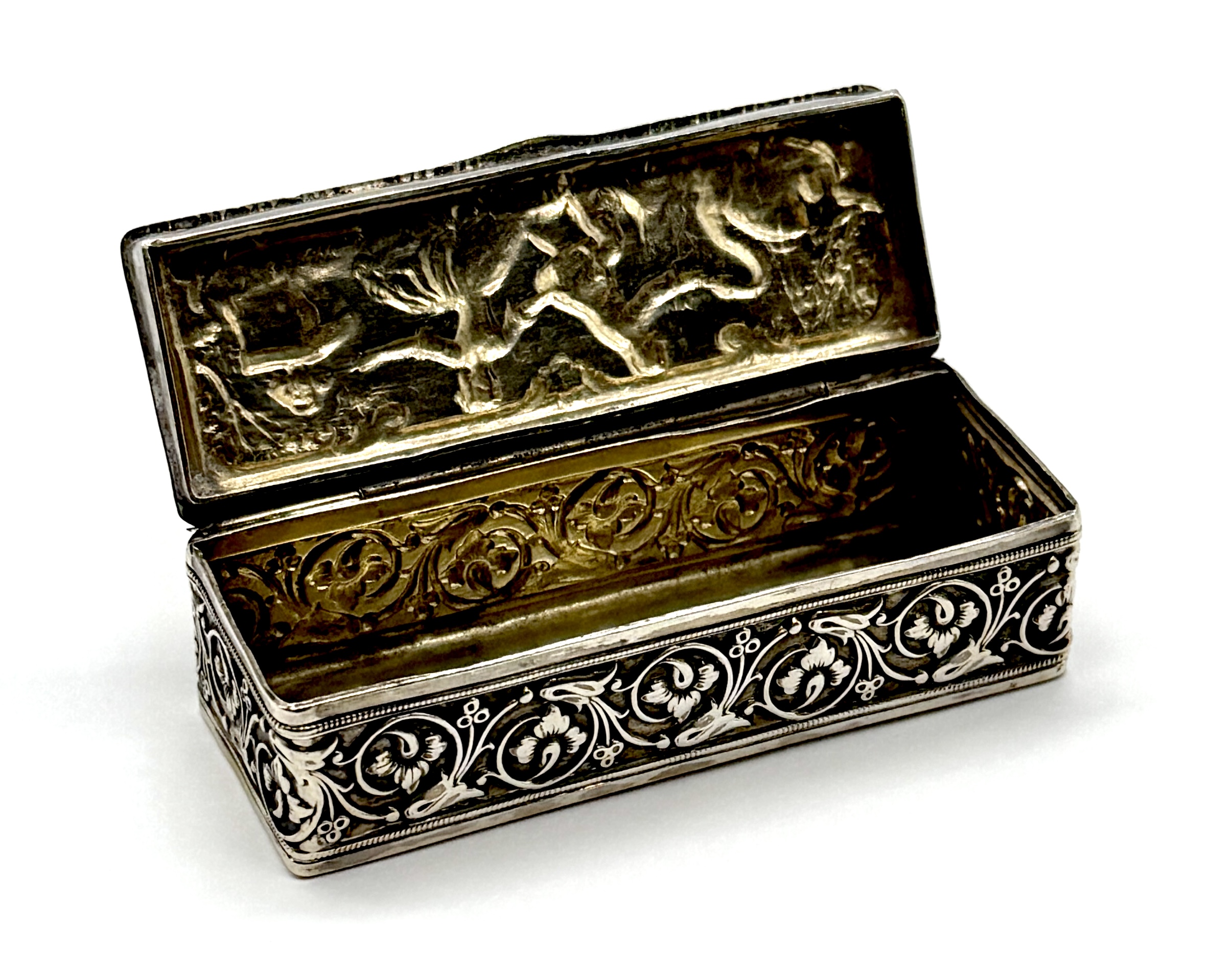 A hallmarked silver box with repousse decoration depicting a classic ...