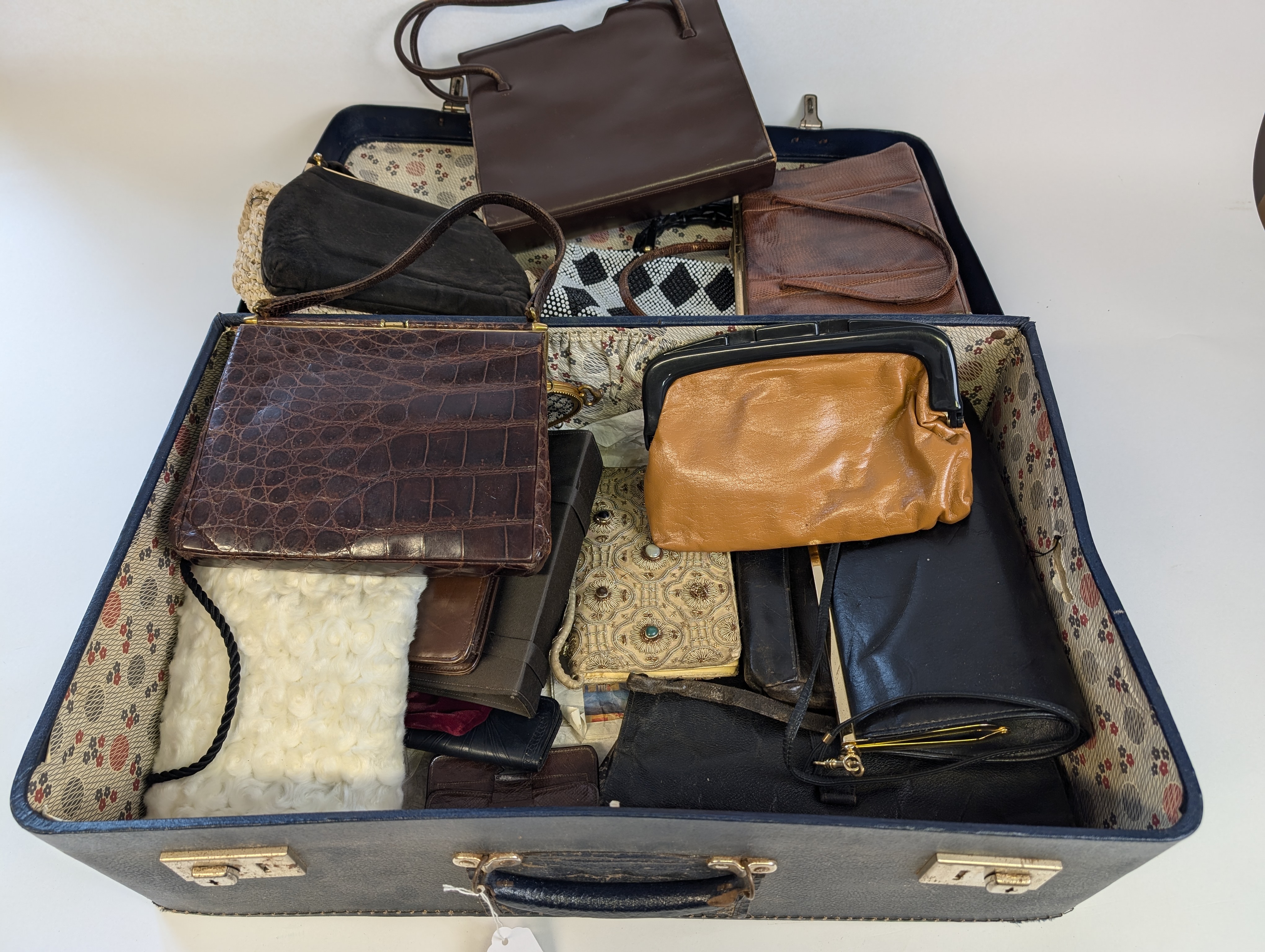A collection of handbags and purses within a black suitcase. Various ...