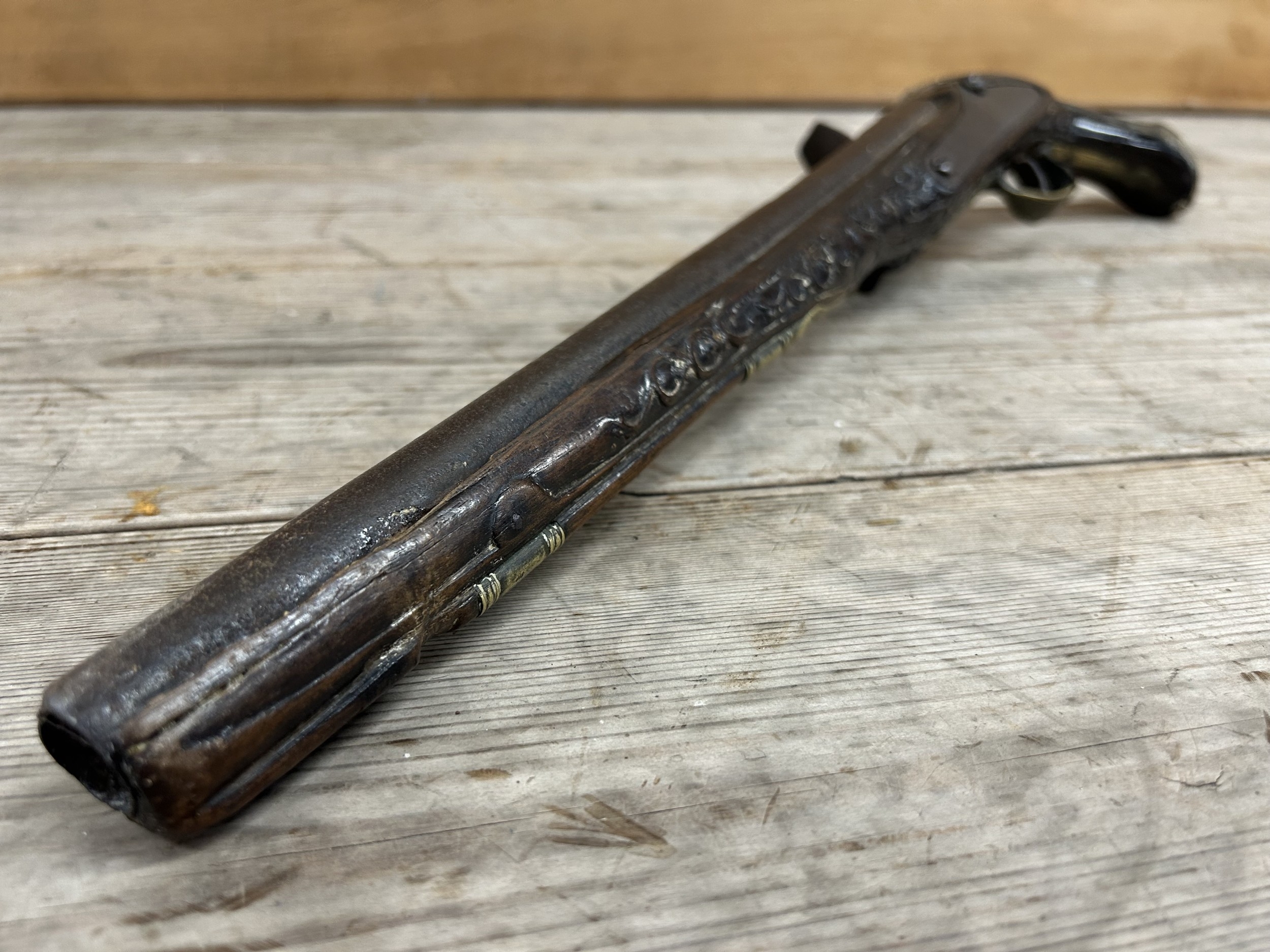 Early carved wood and brass flintlock pistol, having intricate scrolled ...