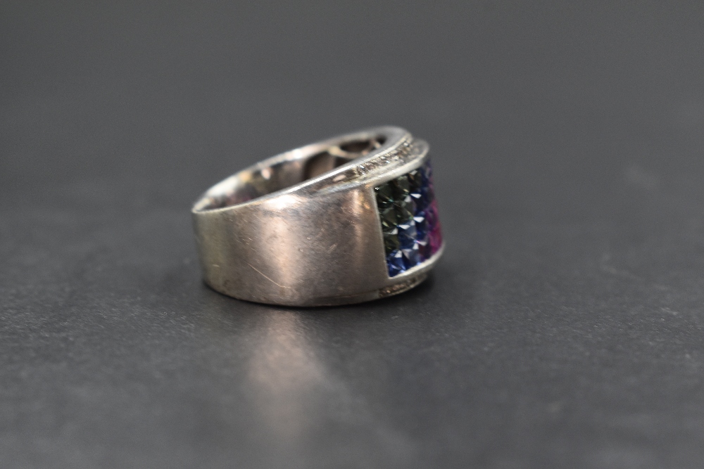A silver band ring of broad form having an inset panel of 36 rainbow ...