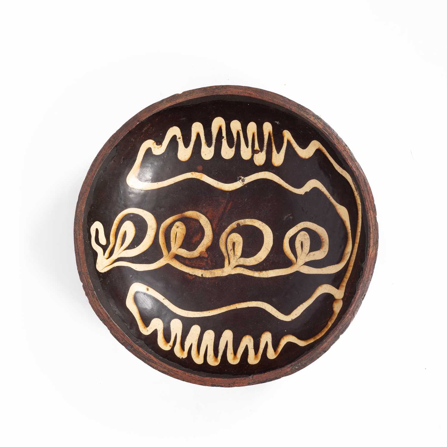 An English slipware bowl, late 18th Century, the circular redware body ...