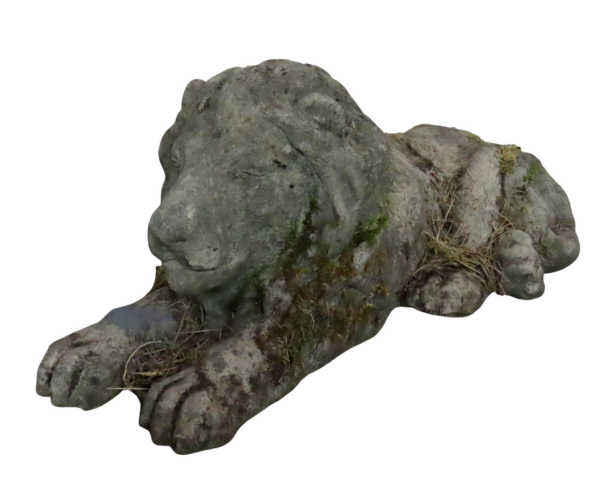 A 20th century reconstituted stone garden statue of a lion at rest ...