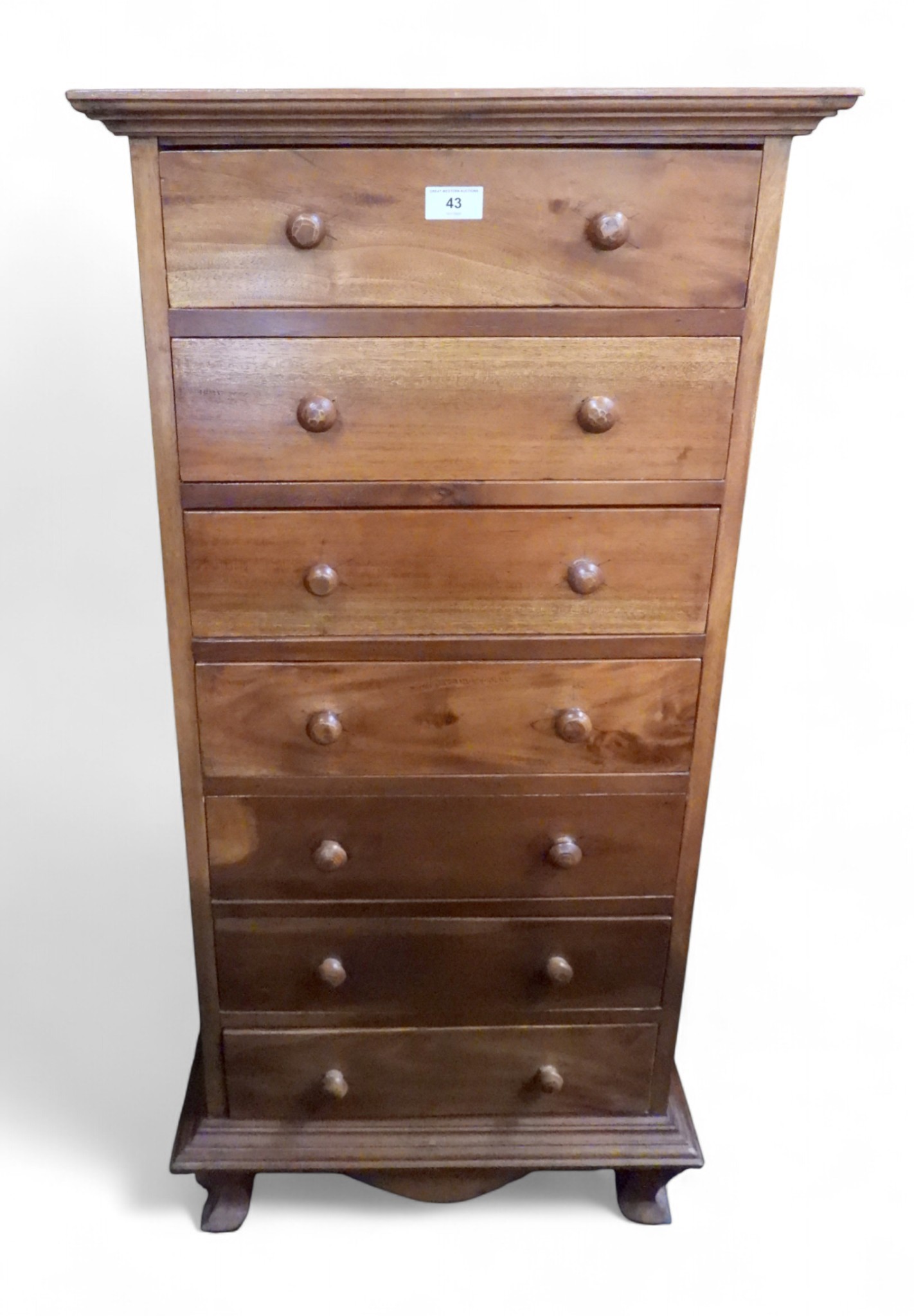 A contemporary stained teak narrow chest of seven drawers with turned ...
