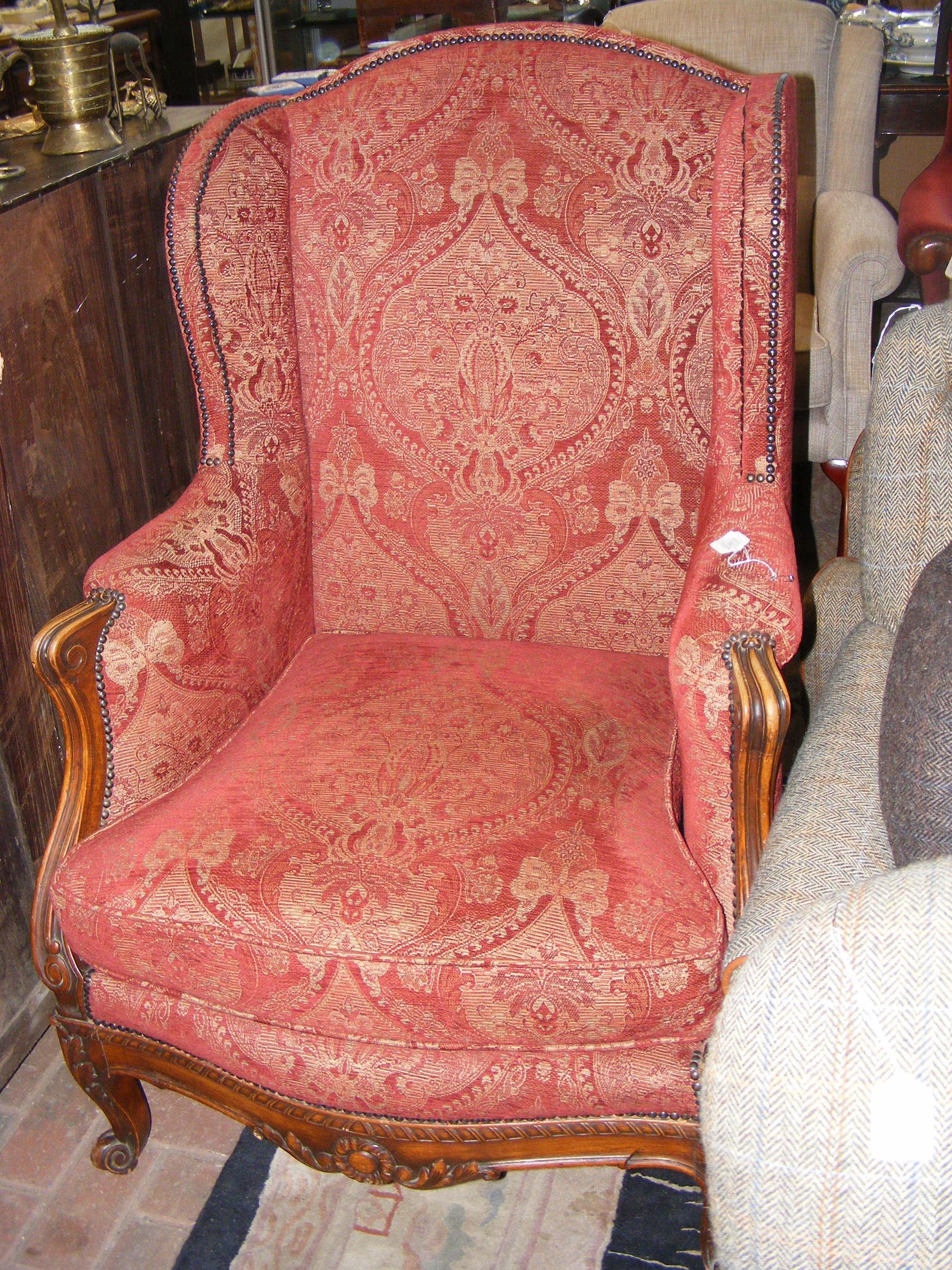 A wing back armchair upholstered in red brocade