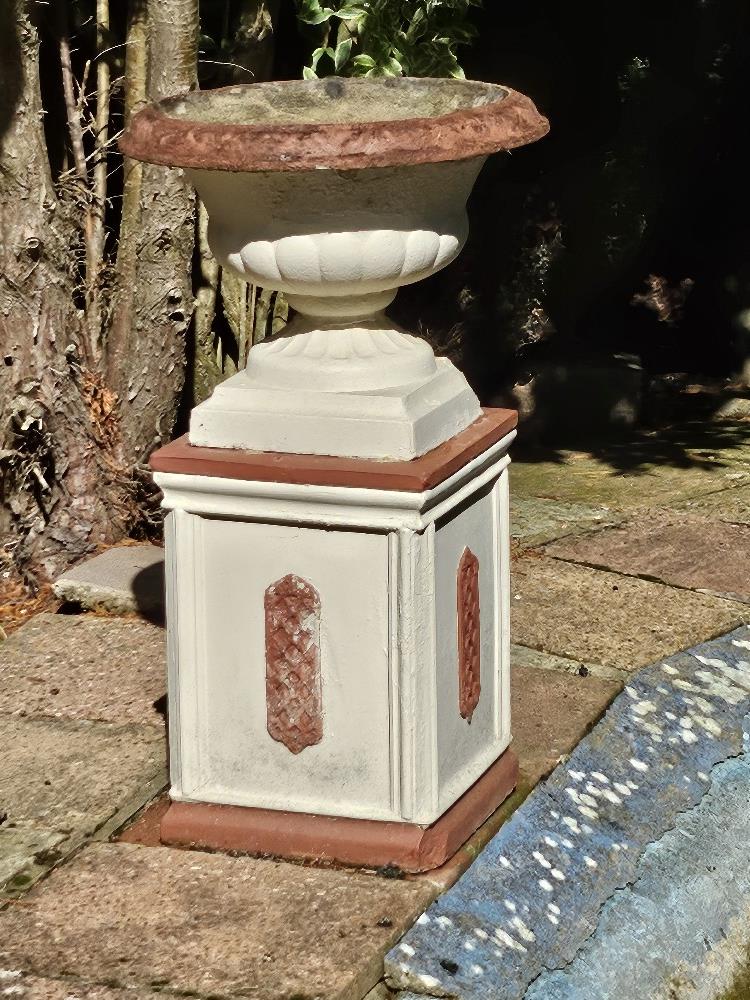 A pair of cast concrete classical garden urns raised over square shaped ...