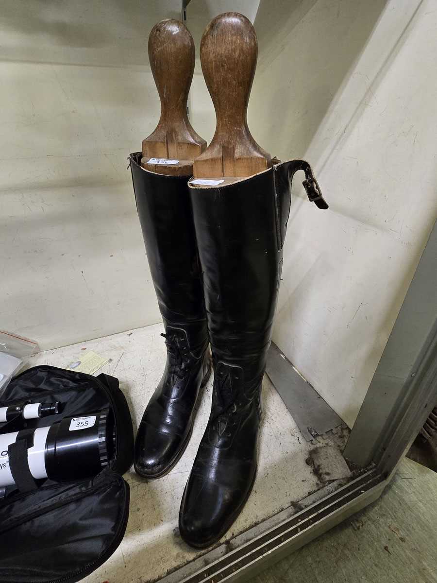 A pair of black leather riding boots containing a pair of wooden shoe lasts