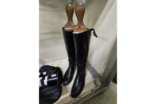 A pair of black leather riding boots containing a pair of wooden shoe lasts