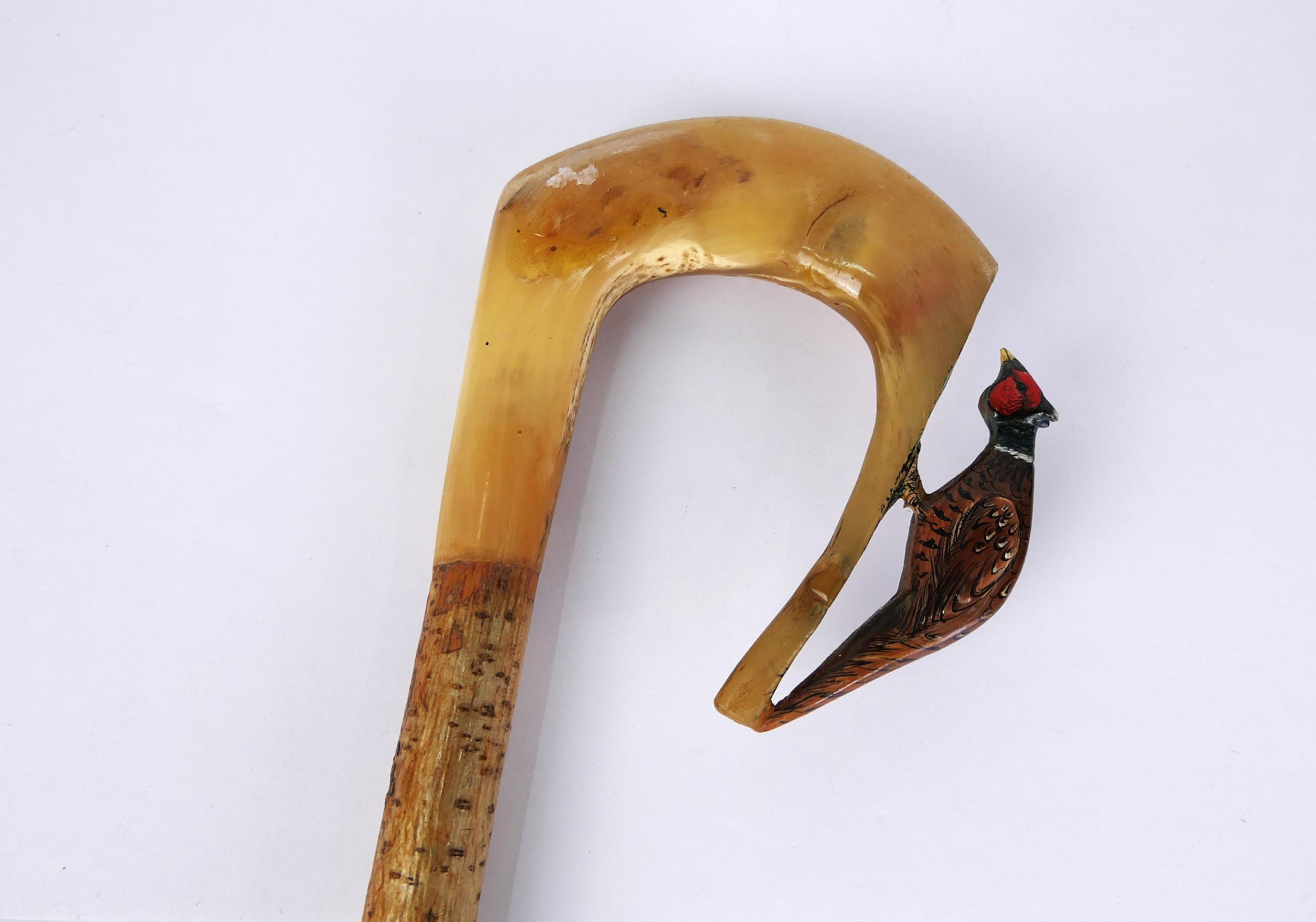 A hazel shafted walking stick with tup horn handle with carved pheasant ...