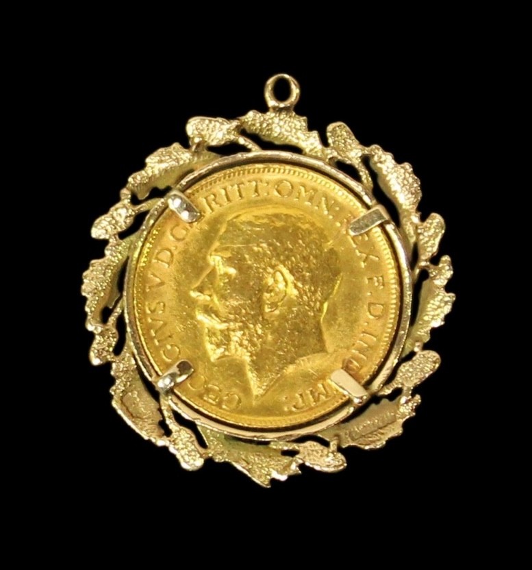 A George V 22ct gold full Sovereign, claw-set in circular acorn and oak ...
