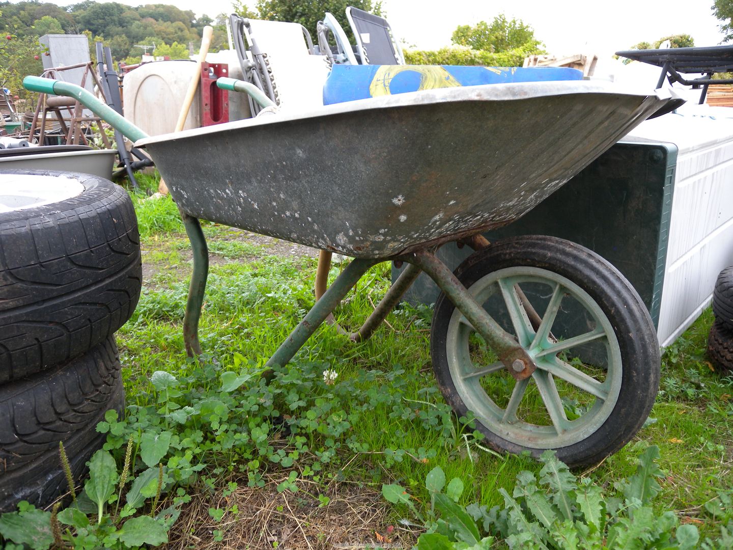 A wheelbarrow on solid tyre containing motorcycle parts, etc.