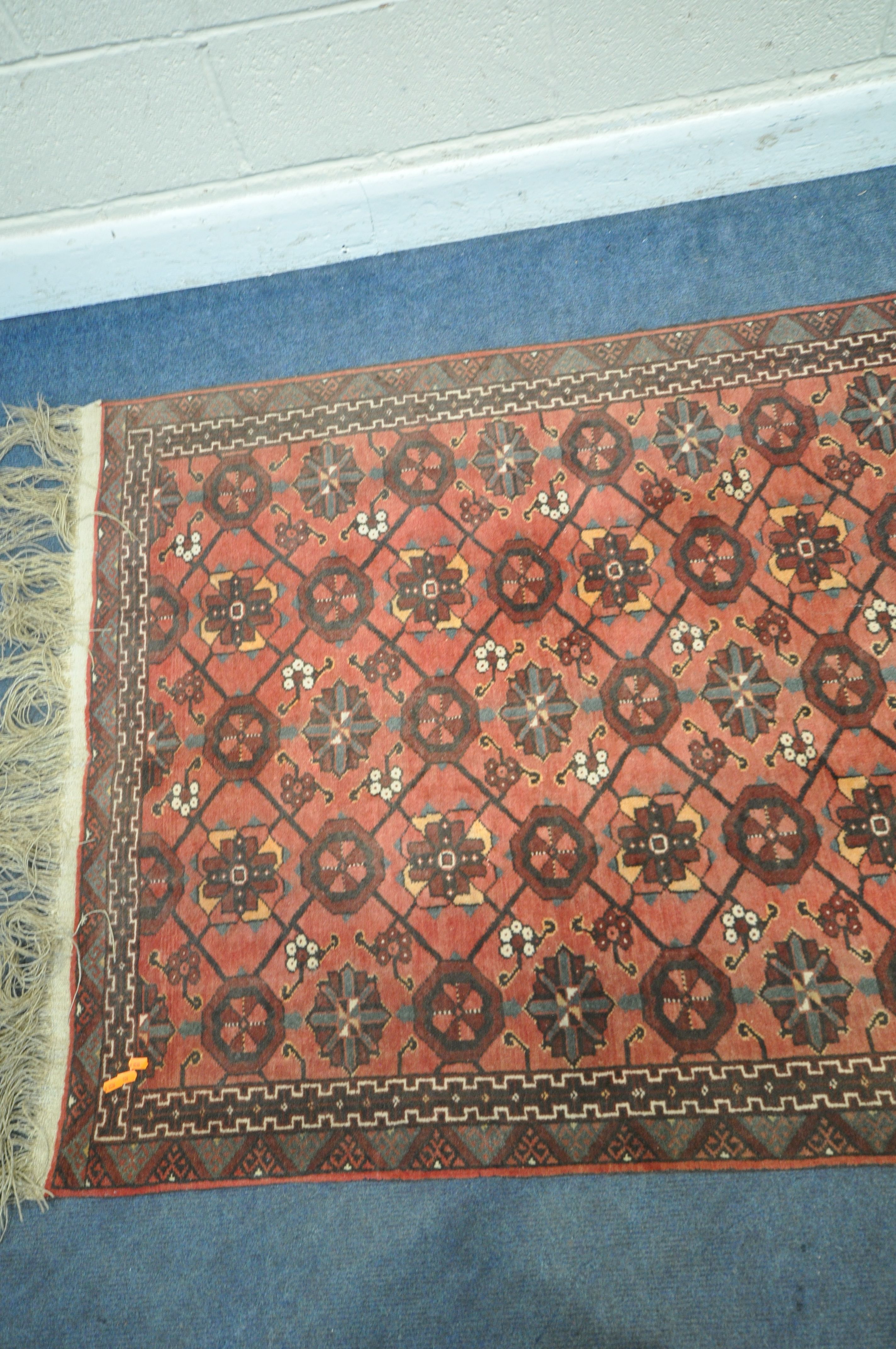 A RED GROUND WOOLLEN RECTANGULAR RUG, with repeating geometric patterns ...