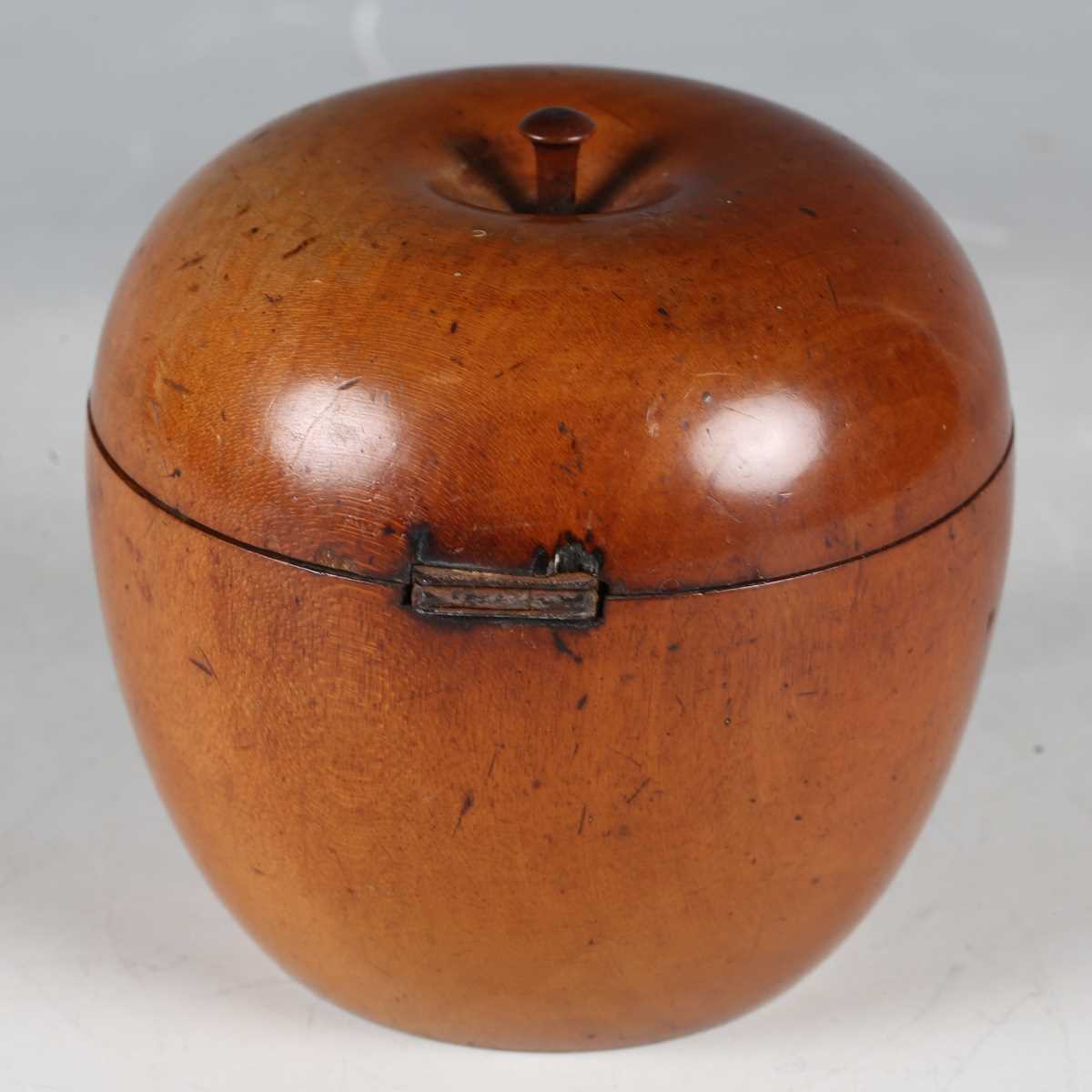 A George III turned apple tea caddy, the hinged lid with carved stalk ...