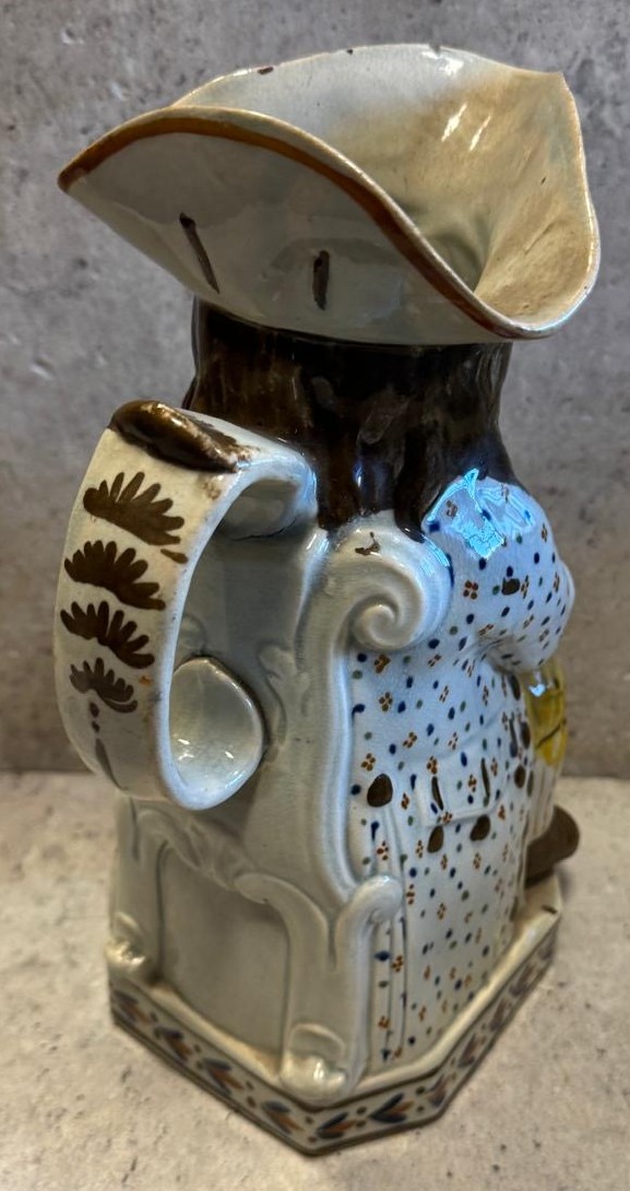 An early pottery Toby jug of typical form decorated in bright colours ...
