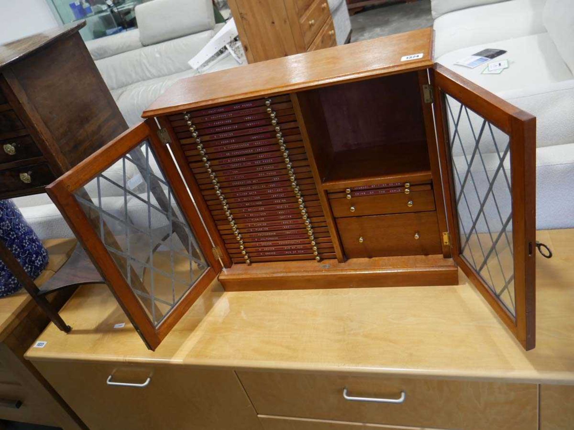 Glazed hanging coin collection cabinet with multiple labelled coin drawers