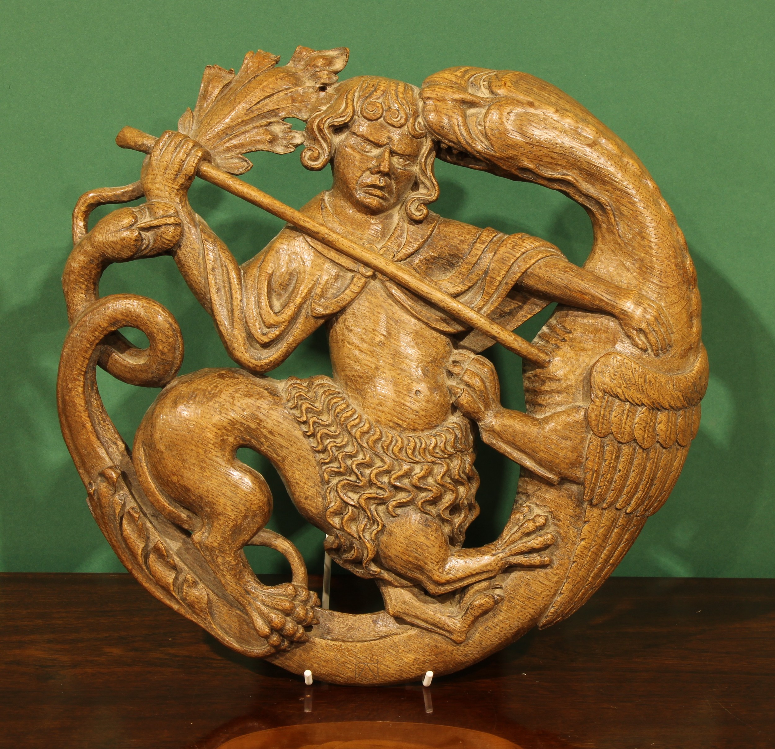 A Gothic Revival oak shaped circular boss, carved as a centaur battling ...
