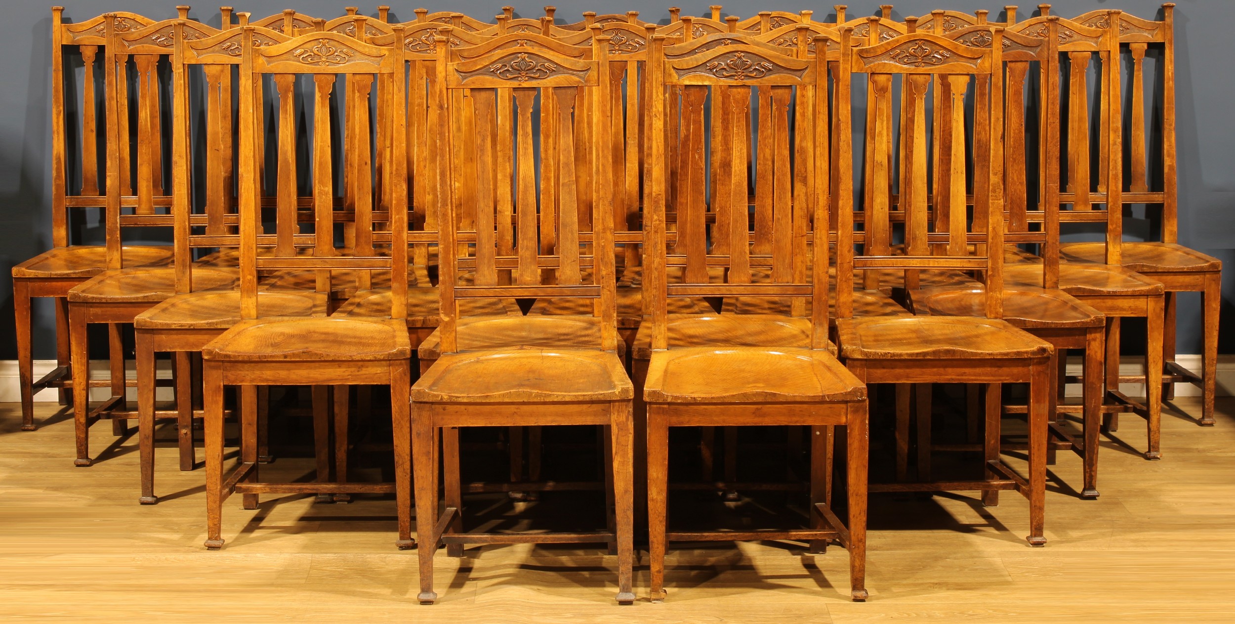 A set of twenty-four Arts & Crafts oak dining chairs, each cresting ...