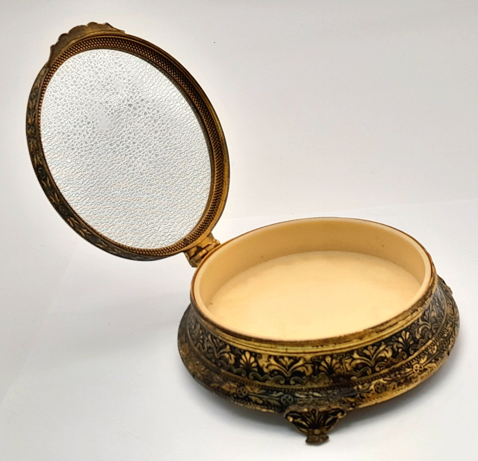 A vintage gilt metal circular jewellery trinket box with mirror inside ...