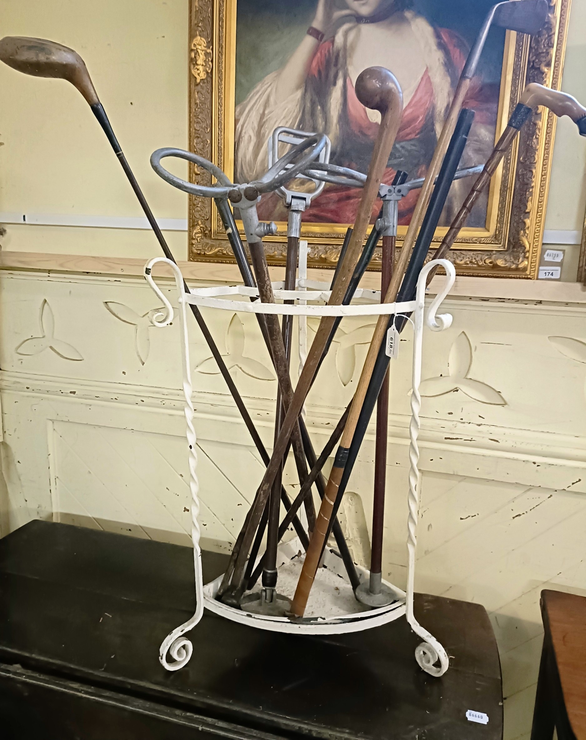 A group of walking sticks, two golf clubs, and a white painted wrought ...