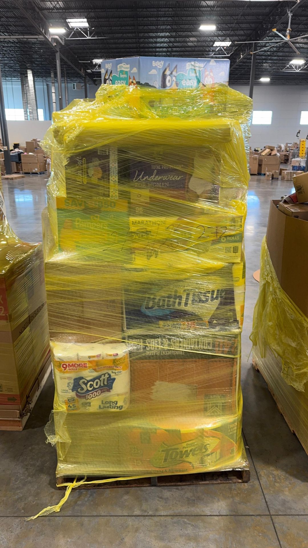 tall pallet full of paper towels, toilet paper, Crock-Pot diapers and more