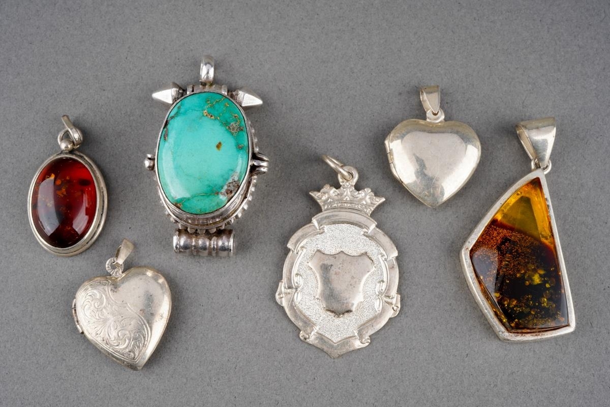 A collection of silver pendants. To include two reconstituted amber ...