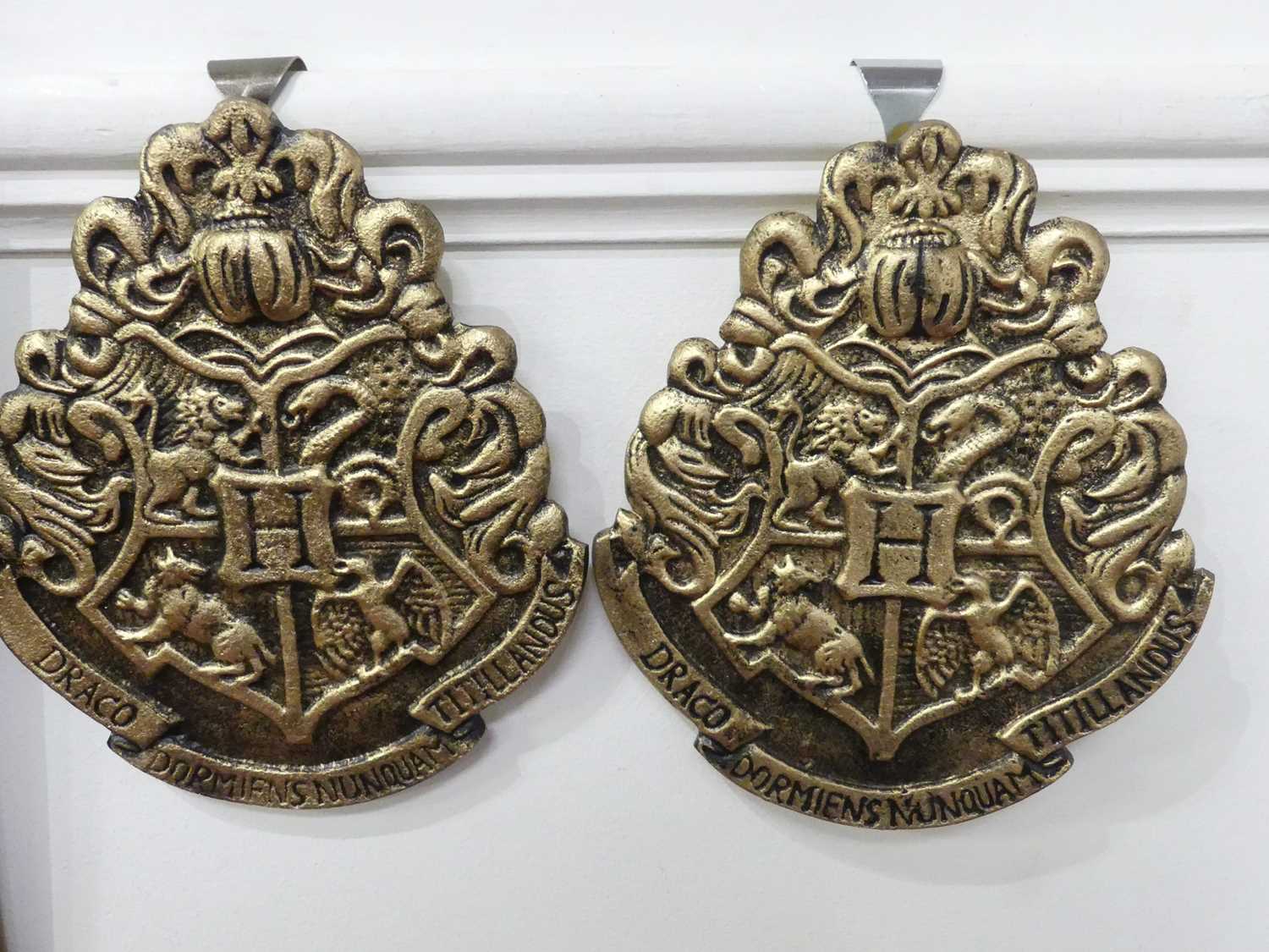 A pair of reproduction cast metal Hogwarts crests, 27 x 23cm
