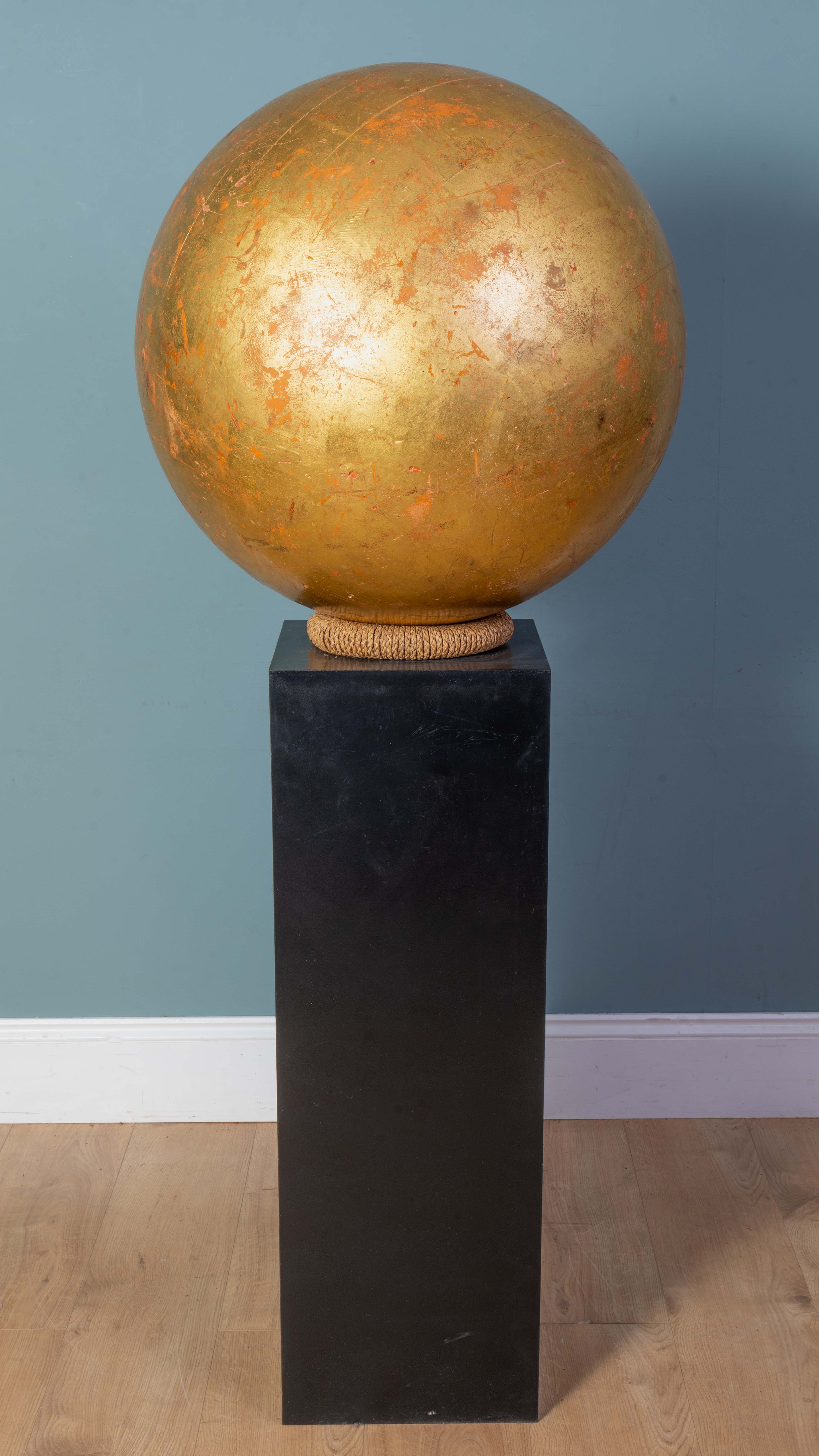 A large gilt sphere on a plinth The glit sphere, possibly of plaster ...