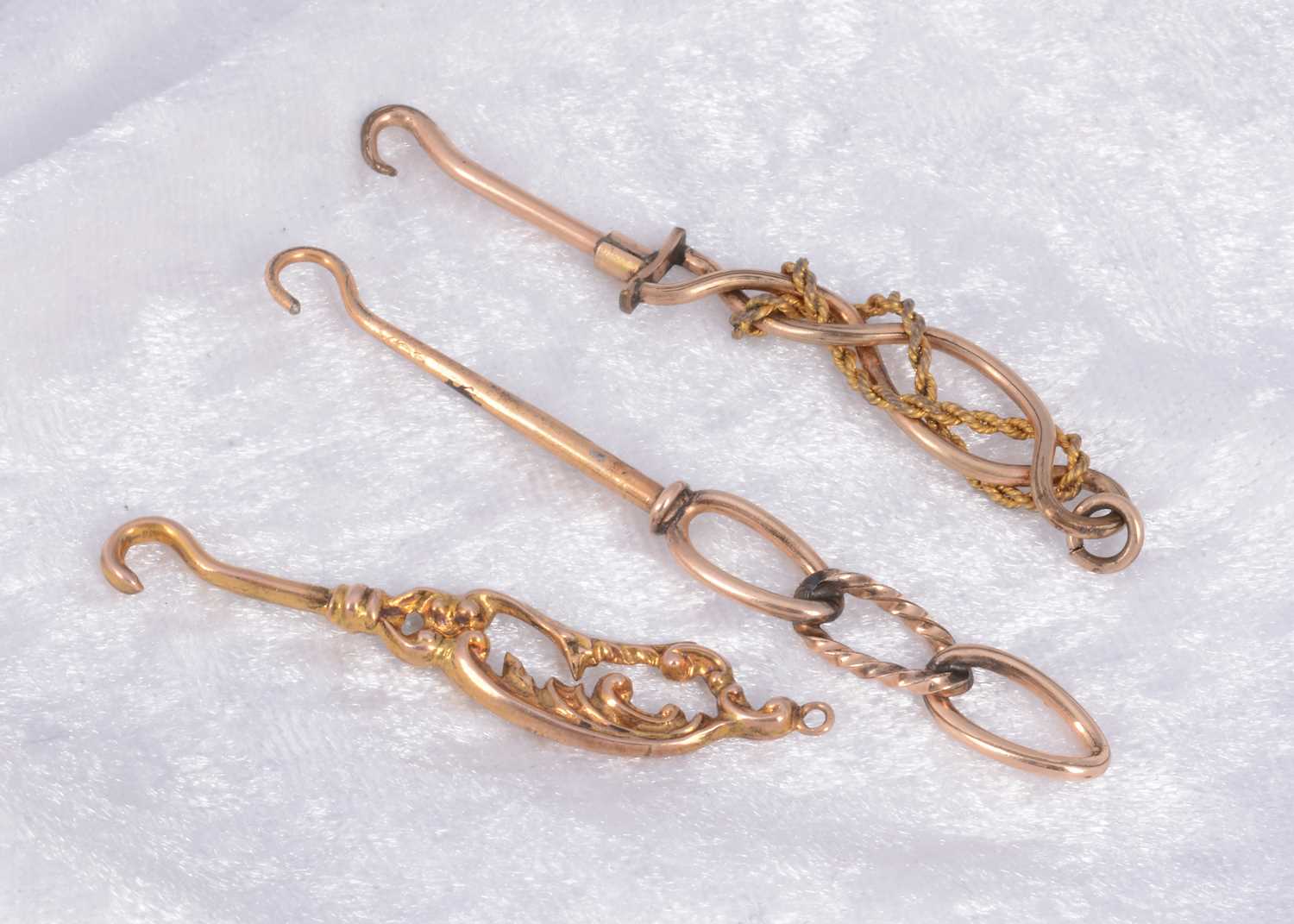 Three ornate yellow and gilt metal button hooks, including an openwork ...
